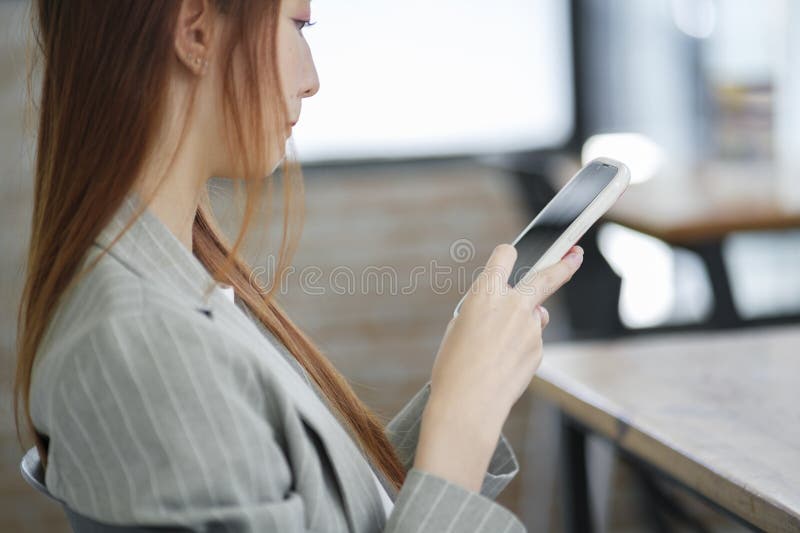 Businesswoman Checking Mobile Device in Office. Stock Photo - Image of ...