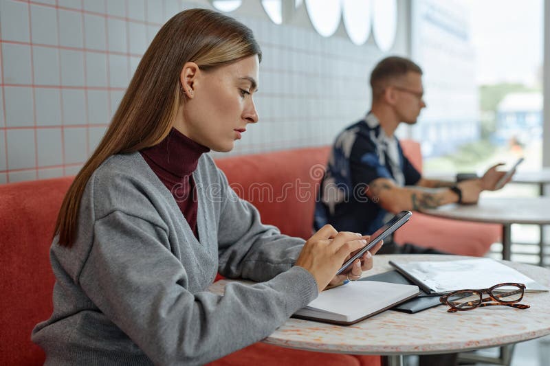 Businesswoman Checking Phone while Working at Table in Cafe Stock Photo ...
