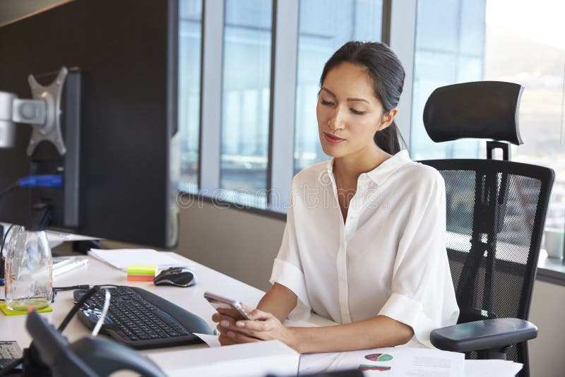 Businesswoman at Desk Checking Messages on Mobile Phone Stock Image ...