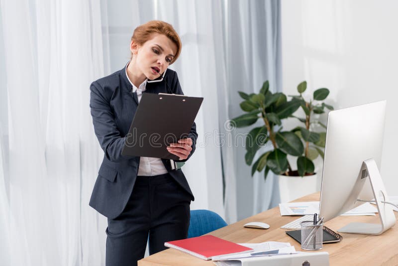 Businesswoman with Documents Talking on Smartphone at Workplace Stock ...