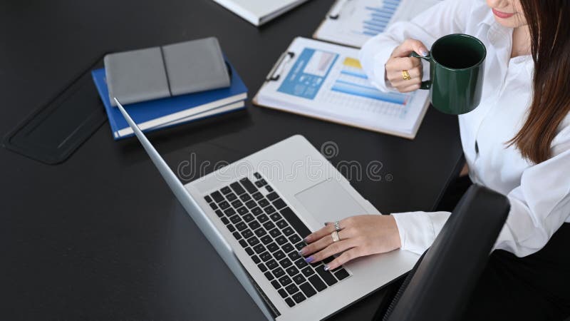 Businesswoman Drinking Hot Coffee and Analyzing Data Report on Laptop ...