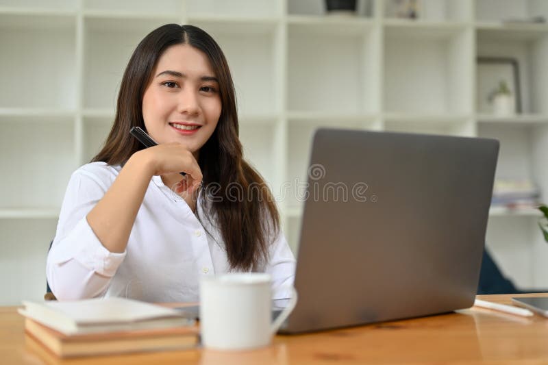 Businesswoman Or Female Employee Sits At Her Office Desk With A Laptop