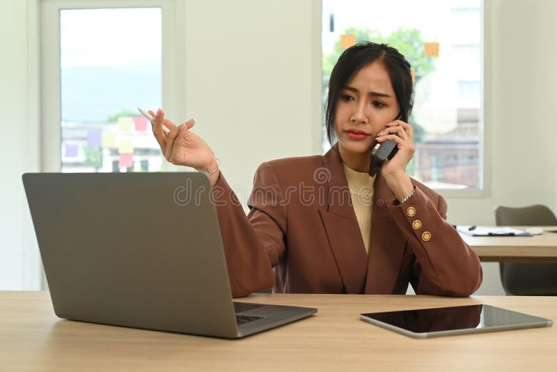 Businesswoman Having Phone Conversation with Client and Using Laptop ...