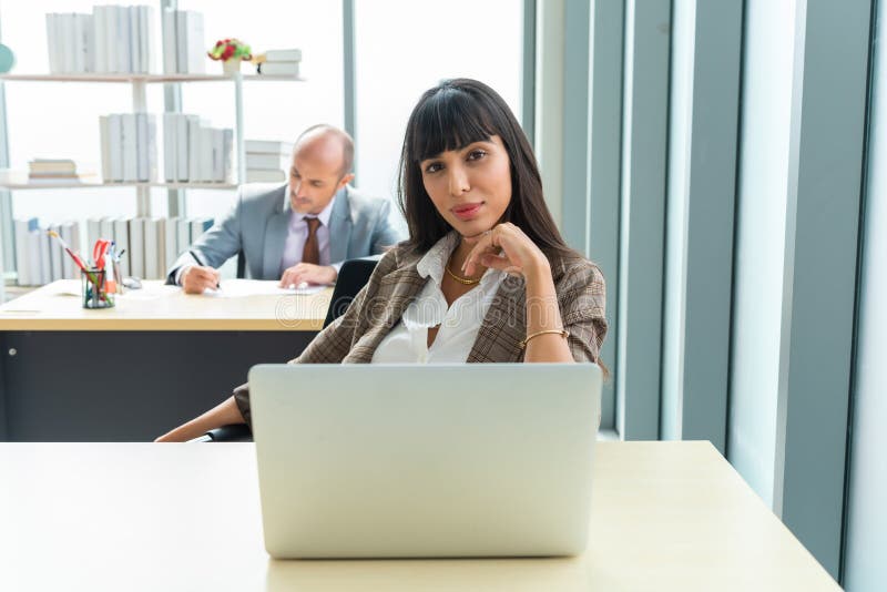 Businesswoman Looking at Camera Behind Laptop while Doing Some ...