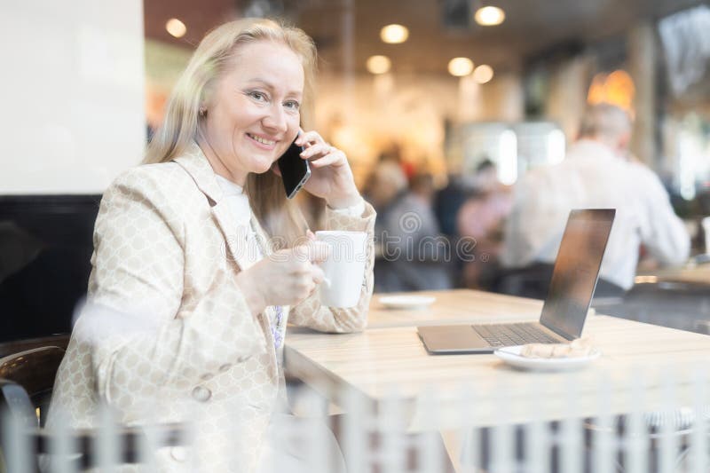 Businesswoman Sitting at Cafe Table and Talking on Mobile Phone Stock ...