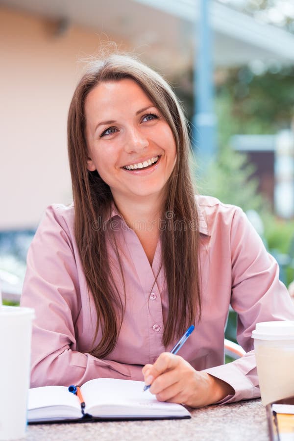 Businesswoman Sitting in a Cafe Writing in Notepad Stock Photo - Image ...