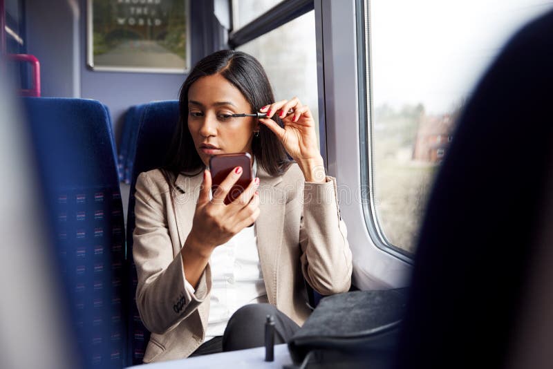 Businesswoman Sitting in Train Commuting To Work Putting on Make Up ...