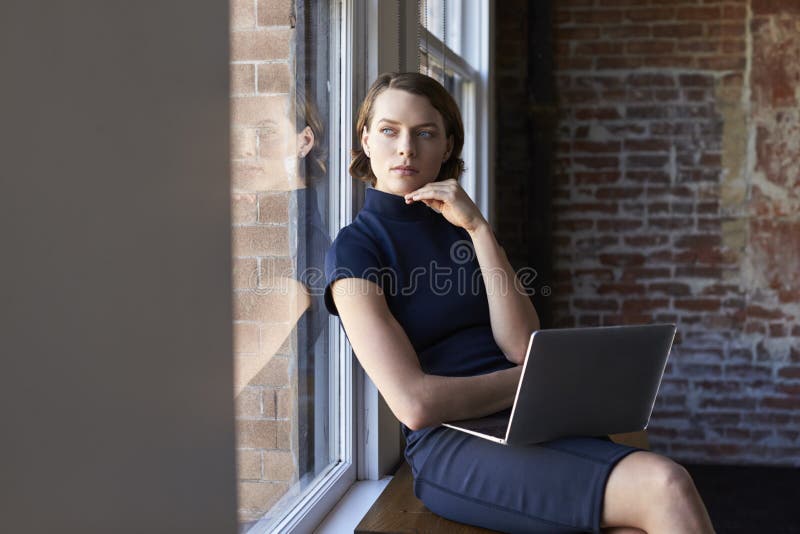 Businesswoman Sitting by Window Working on Laptop Stock Image - Image ...