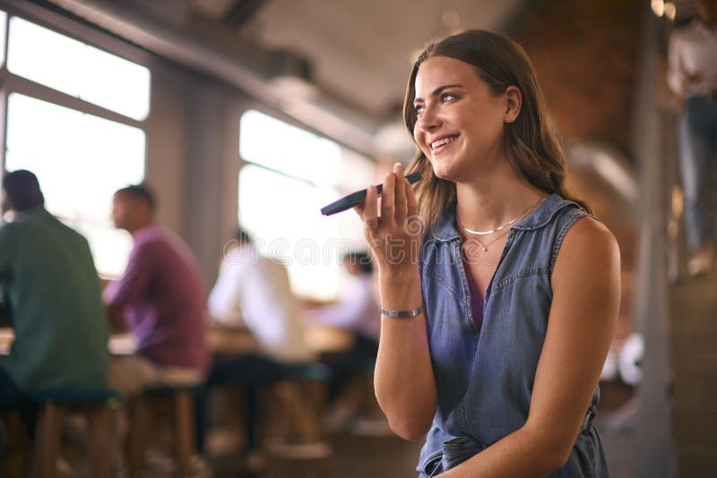 Businesswoman Talking into Mic on Mobile Phone in Open Plan Office with ...