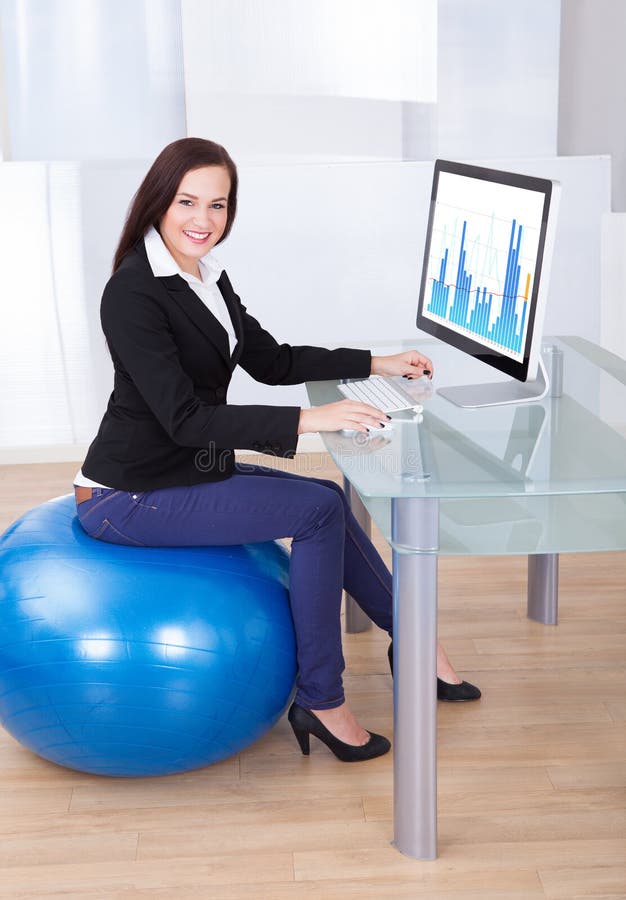 Businesswoman Using Computer while Sitting on Pilates Ball Stock Photo ...