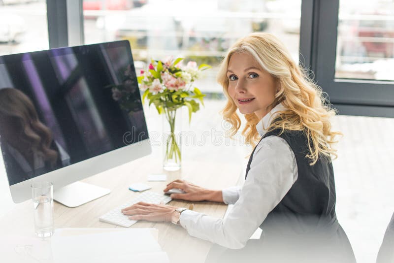 Businesswoman Using Desktop Computer and Looking at Camera Stock Photo ...