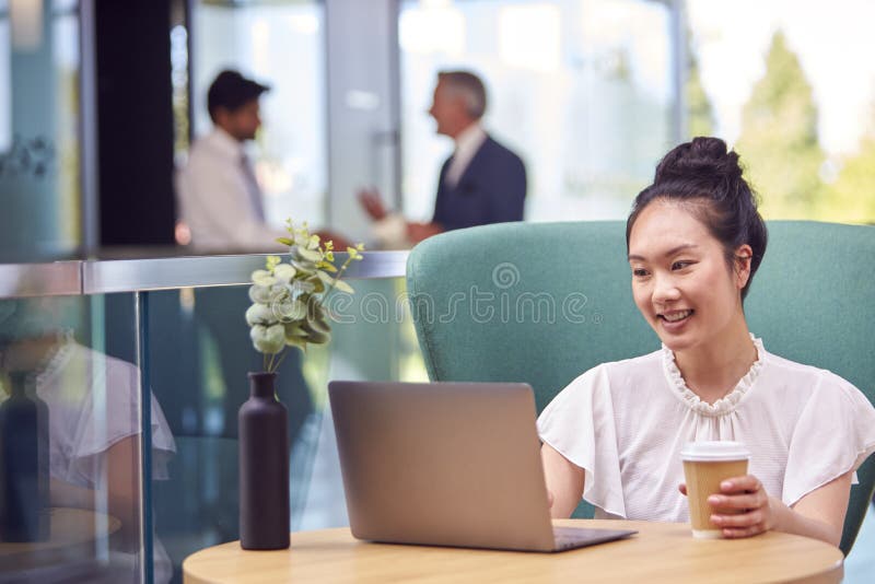 Businesswoman Using Laptop Working at Table in Breakout Seating Area of ...
