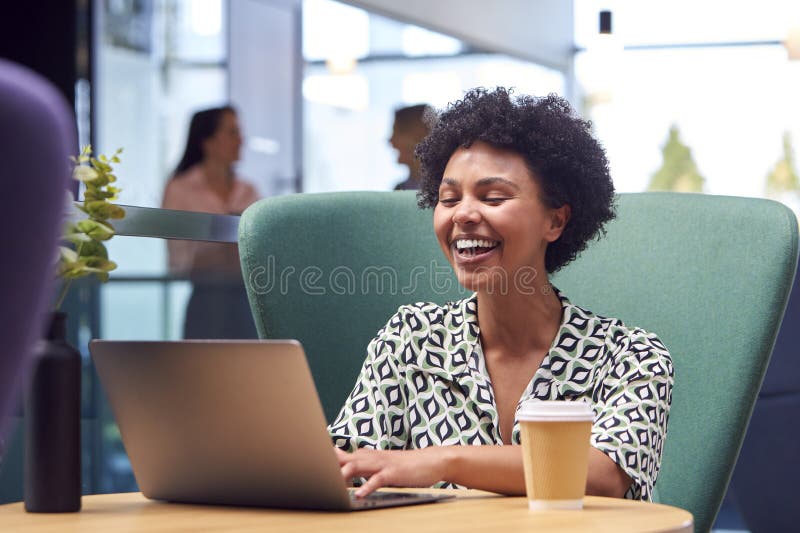 Businesswoman Using Laptop Working at Table in Breakout Seating Area of ...