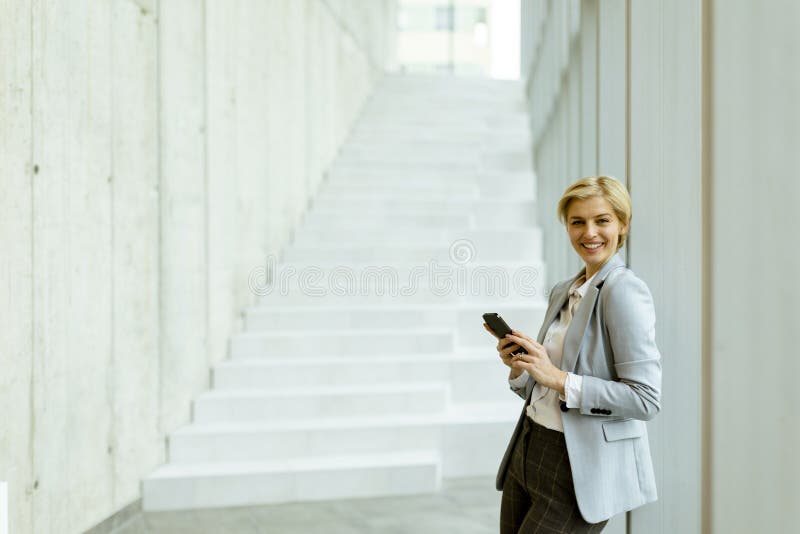 Businesswoman Using Mobile Phone on Modern Office Hallway Stock Photo ... Businesswoman Using Mobile Phone on Modern Office Hallway Stock Photo ...