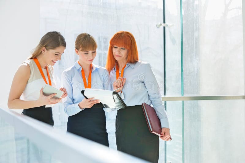 Businesswomen Doing Paperwork by Railing in Office Stock Image - Image ...