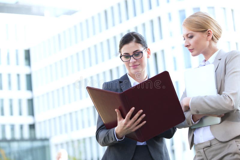 Businesswomen Reading Folder while Standing Outside Office Building ...