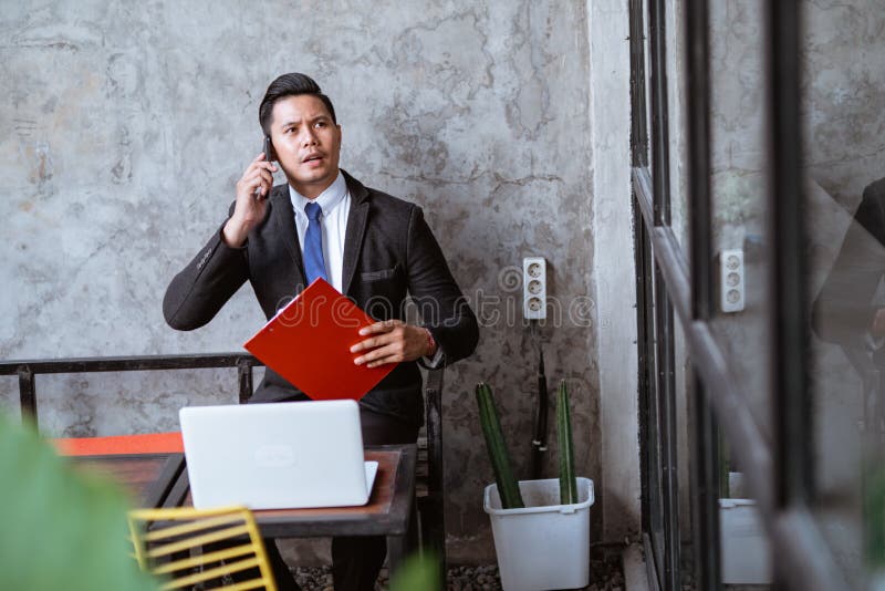 Businessman Having a Discussion through His Phone while Working Stock ...