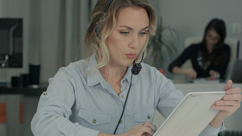 Busy Call Center Agent Using Digital Tablet on a Call at Her Workplace ...