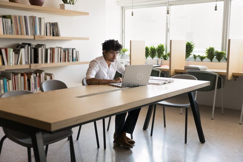 Busy Male Student Engaged in Learning at Library Using Notebook Stock ...
