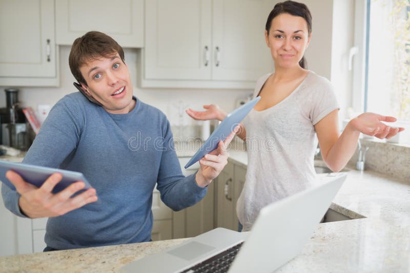 Busy Man Using Two Tablets and Laptop with Wife Holding Hands Up Stock ...