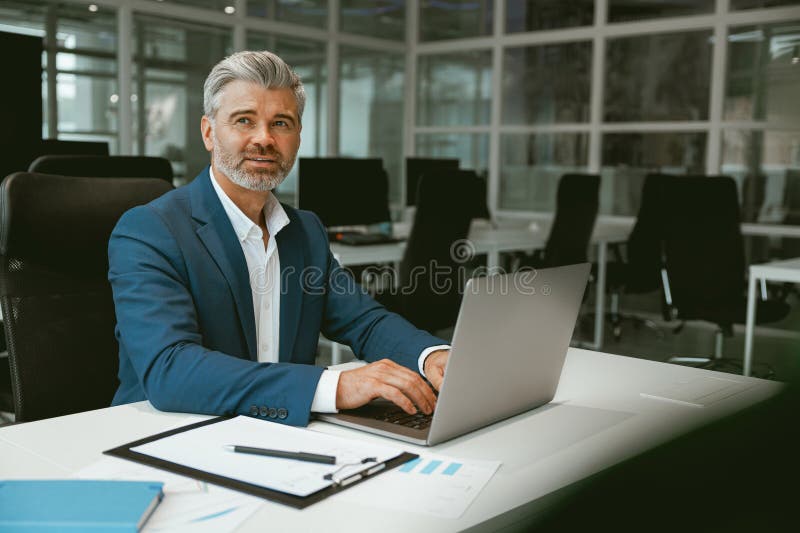 Busy Mature Businessman Workingon Laptop while Sitting in Modern ... Busy Mature Businessman Workingon Laptop while Sitting in Modern ...