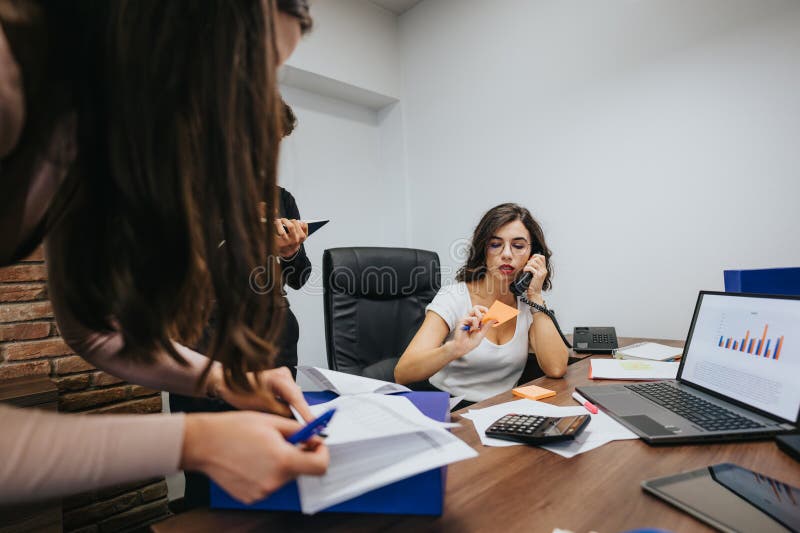 Focused Businesswoman Multitasking with Phone and Notes at a Busy ...