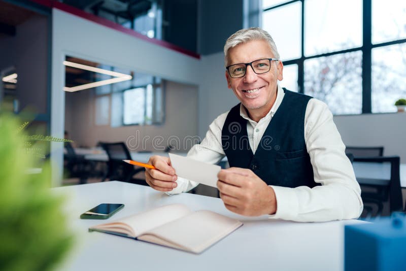 Busy Senior Man Sitting at Office Desk with Papers and Making Notes ...