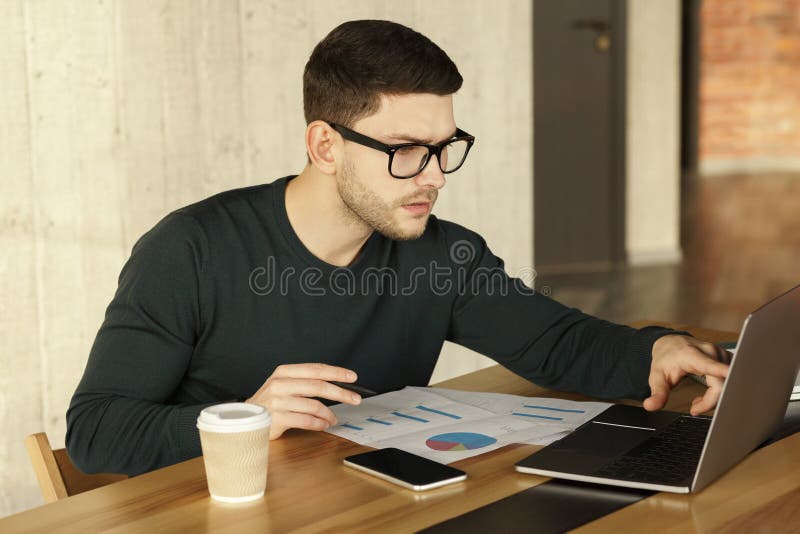 Busy Young Man Working with Charts Sitting at Workplace Indoor Stock ...