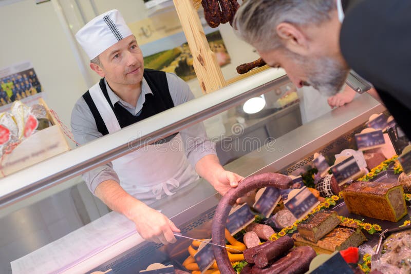 Butcher serving a customer stock photo. Image of store - 259684192