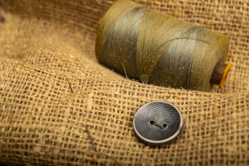 Button Sewn To Burlap with a Rough Texture and a Spool of Thread. Close ...