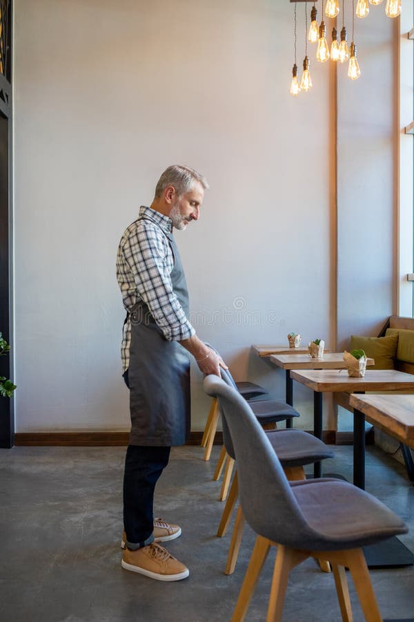 Waiter Putting Chairs in Order in the Cafe Premises Stock Image - Image ...