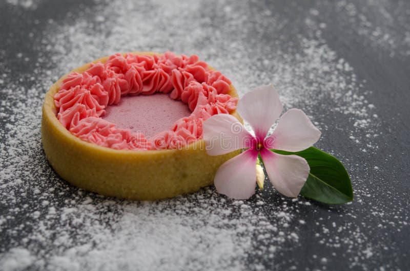 Cake with Cream and White Flower on a Black Surface, Sprinkled with ...