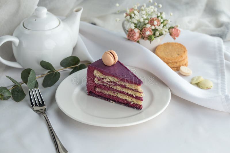 Cake Slice in Purple Glaze Decorated Macaroon and Teapot on the Table ...