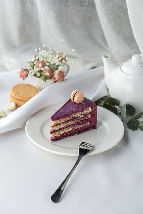 Cake Slice in Purple Glaze Decorated Macaroon and Teapot on the Table ...