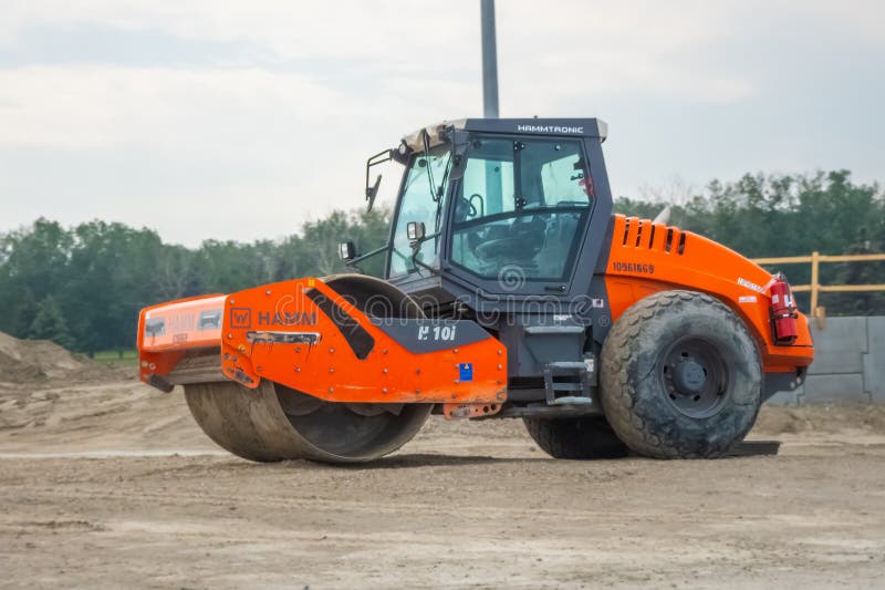 An Orange Hamm H 10i Compactor Stands Ready on a Dirt Construction Site ...