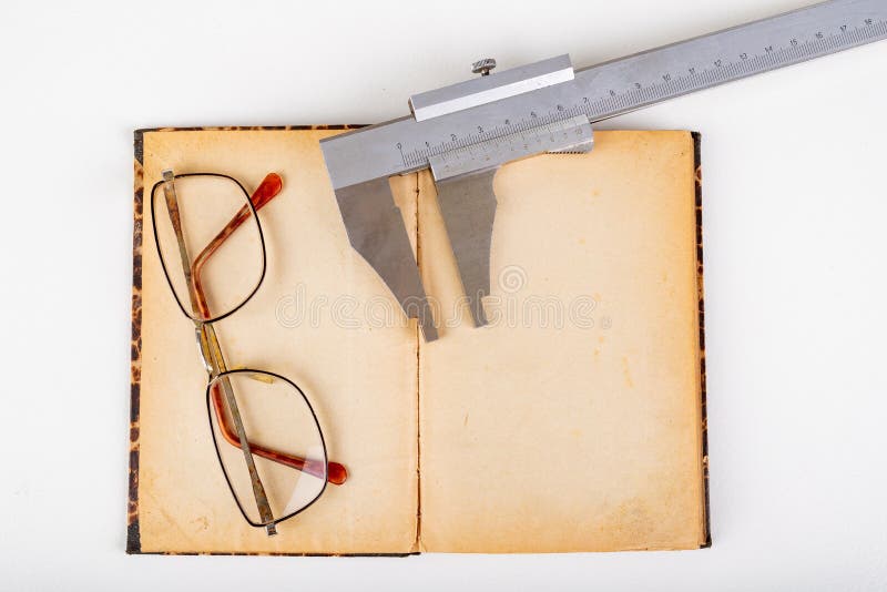 Caliper and Old Book with Glasses on a White Table. Workshop ...
