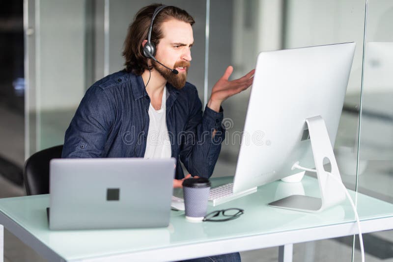 Angry Call Center Operator Working at His Desk on Computer and Laptop ...