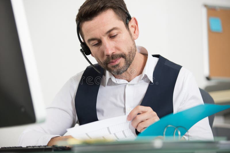 Call Centre Operator Wearing Headset Looking Up Information Stock Image ...