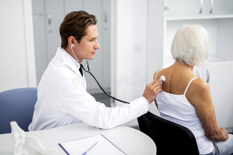 Calm Doctor Wearing Stethoscope and Examining the Patient Stock Image ...
