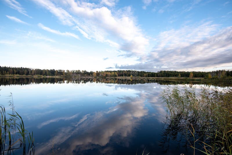 Calm Lake in Bright Sun Light with Reflections of Clouds and Trees and ...