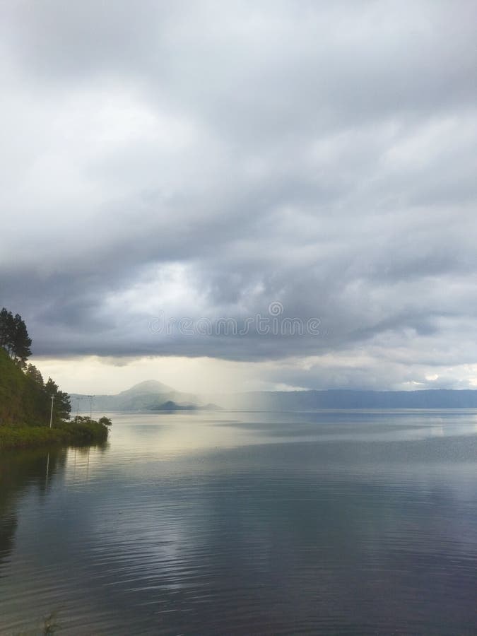 A Calm Lake Under a Cloudy Skysunlight Penetrates the Clouds Stock ...