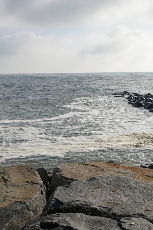 Calm Ocean Inlet with Boulder Jetty As Dark Storm Clouds Approach Stock ...
