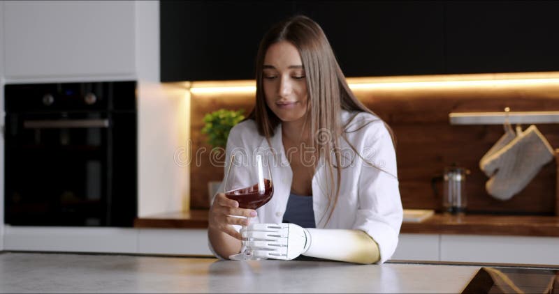 Calm Thoughtful Girl Holds Glass Of Wine In Bionic Arm At Home Woman With Artificial Prosthetic