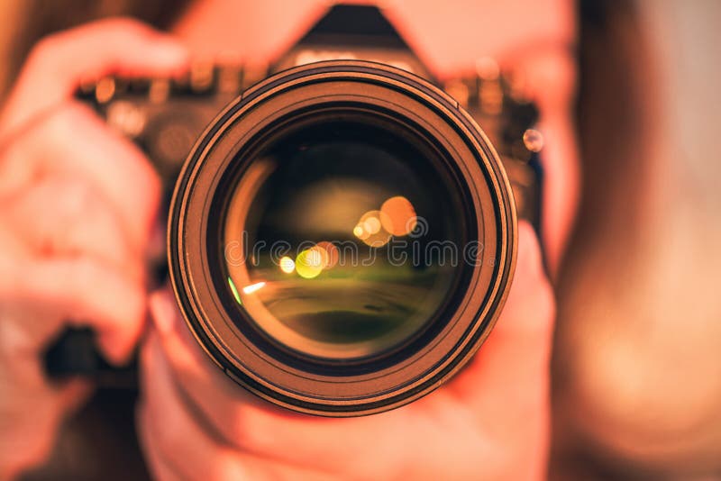 Camera Lens with Sunset Sky Reflections in the Woman Hands. Close - Up ...