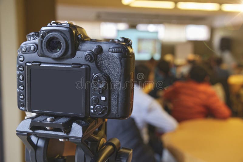 A Camera is Pointed at a Group of People Sitting at a Table Stock Photo ...