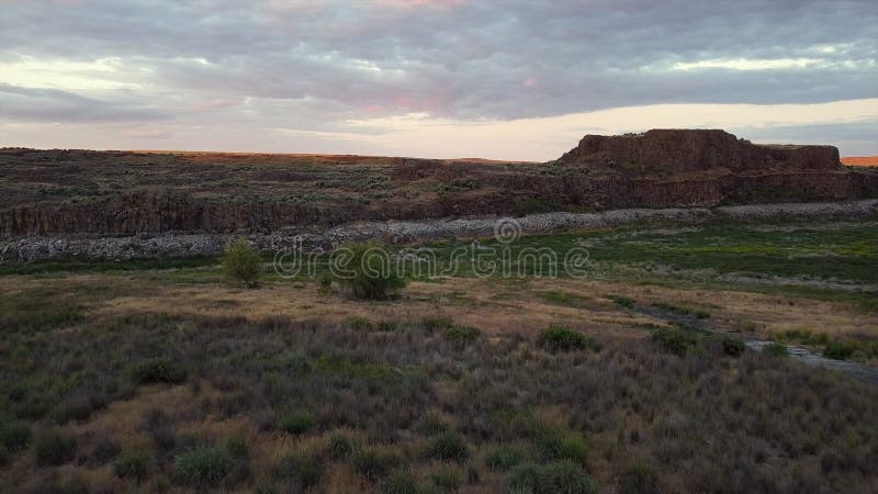 Camera Pulls Back from Rock Cliff Over the Desert Floor at Sunrise ...
