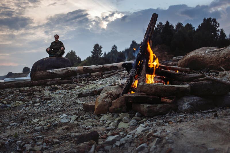 Campfire and Silhouette of Hiker Sitting in a Lotus Pose on Stone Stock ...