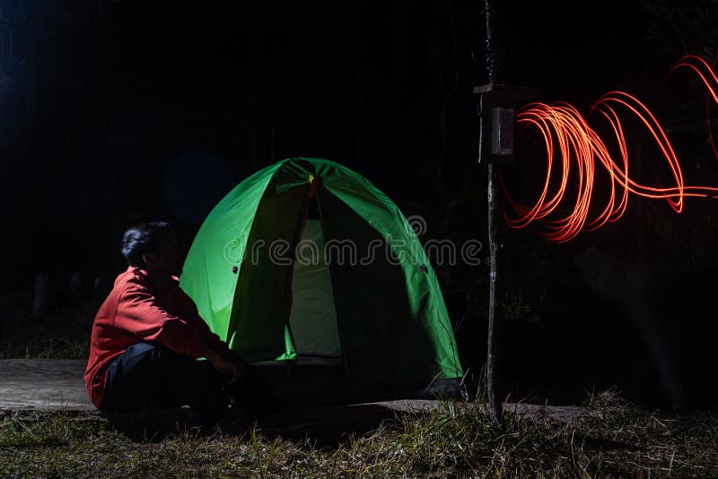 Camping Adventure at Night with Light Trails and Man Sitting in ...