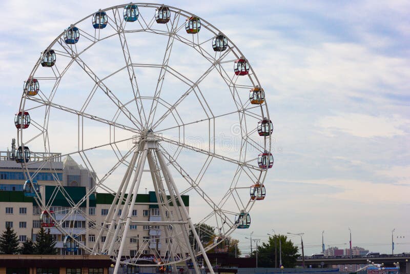 Cantilevered Observation Wheel with Empty Red Cabins on Blue Sky and ...