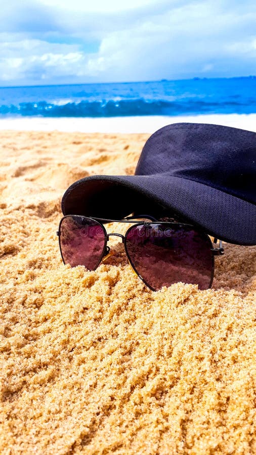 Cap Placed on Top of a Sunglasses on the Beach Sand with the Blue Sea ...